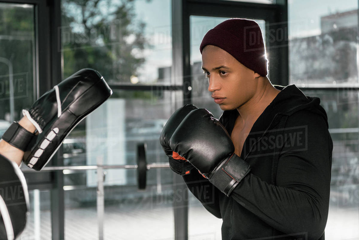 serious african american boxer in boxing gloves practicing with trainer ...