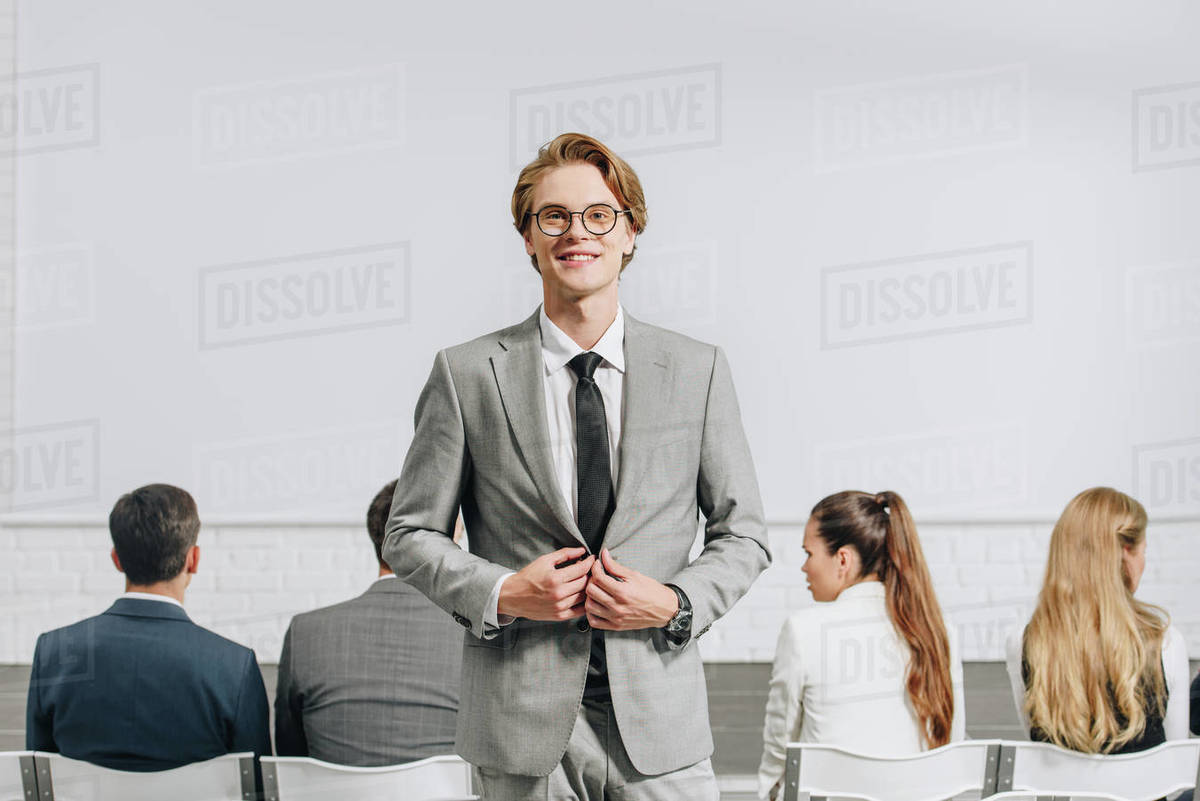 cheerful handsome coach looking at camera during business training in ...