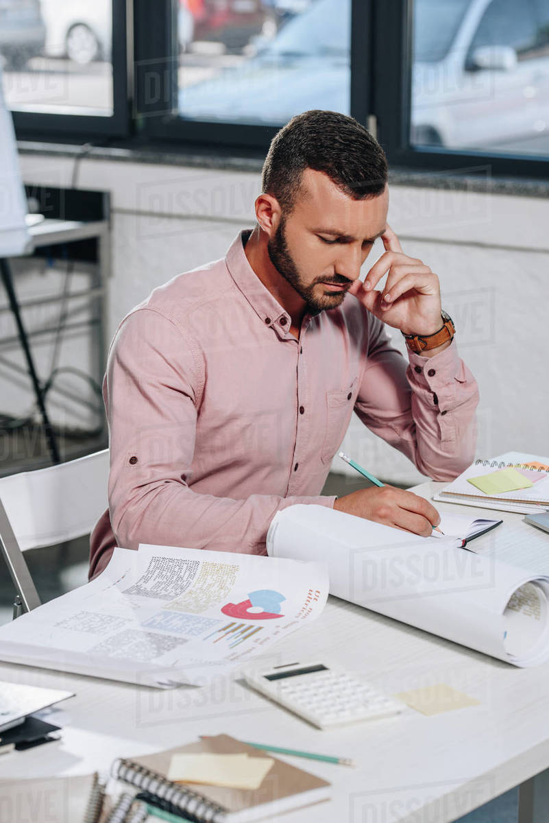 tired pensive businessman writing something in office - Stock Photo ...
