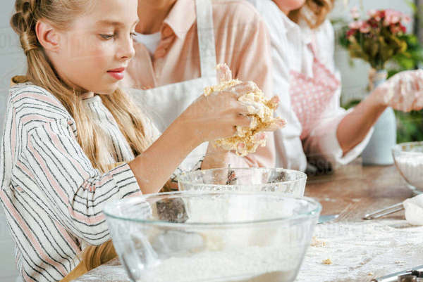 Cropped shot of adorable little child making dough with parents at home ...
