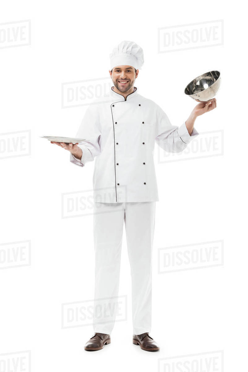 Smiling young chef taking of serving dome from plate and looking at ...