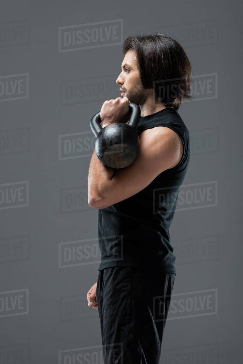 Side view of muscular young man exercising with kettlebell isolated on ...