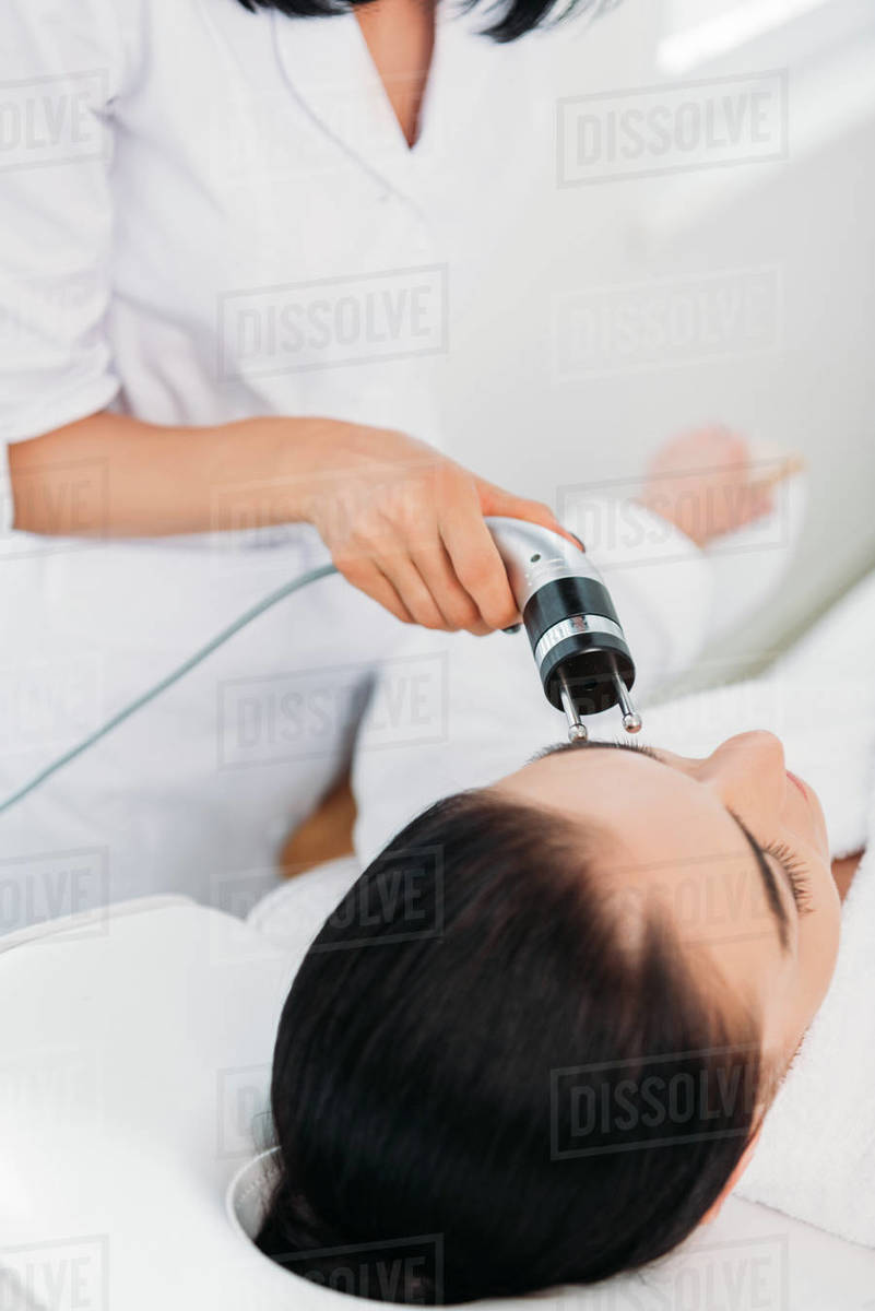 Attractive woman getting facial microcurrent therapy in spa salon ...