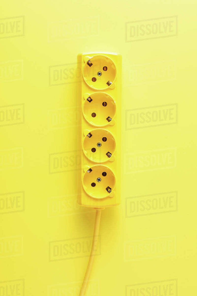 Close-up view of bright yellow socket outlet on yellow background ...