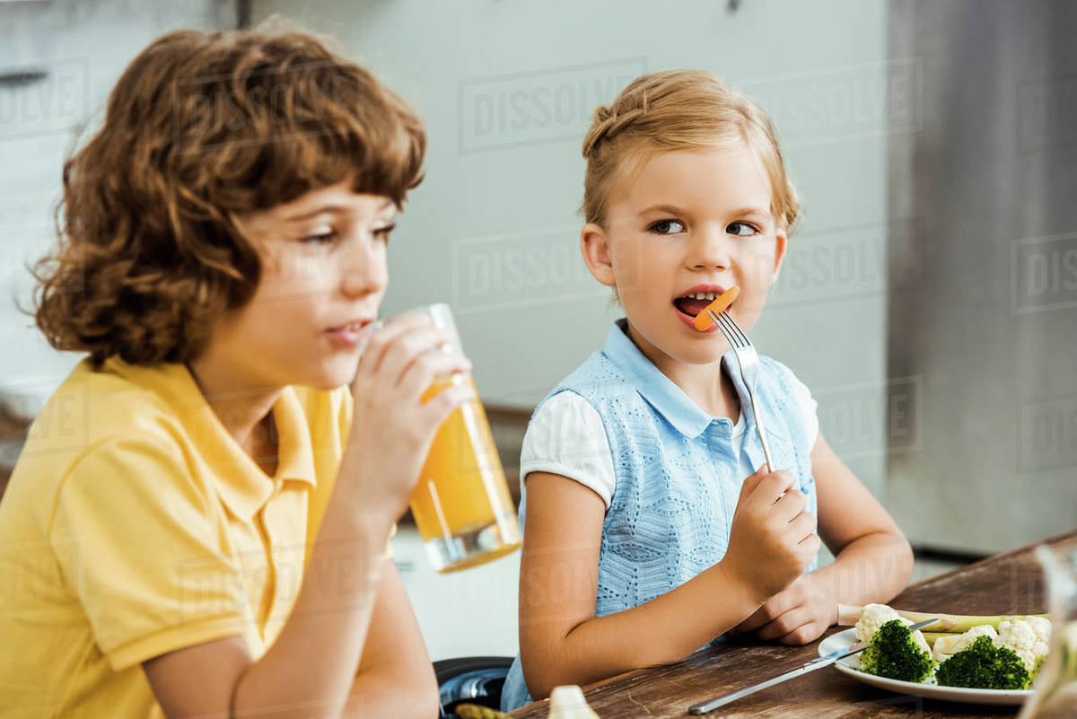 Cute little children eating vegetables and drinking juice - Royalty ...