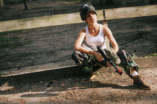 Young female paintballer in white singlet and goggle mask holding ...