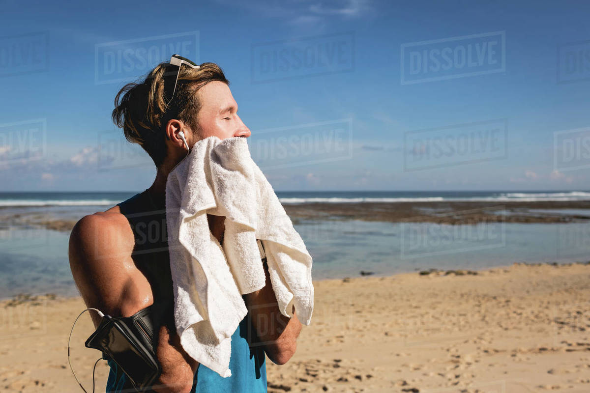 Tired sweaty sportsman with towel on beach - Royalty-free Stock Photo ...