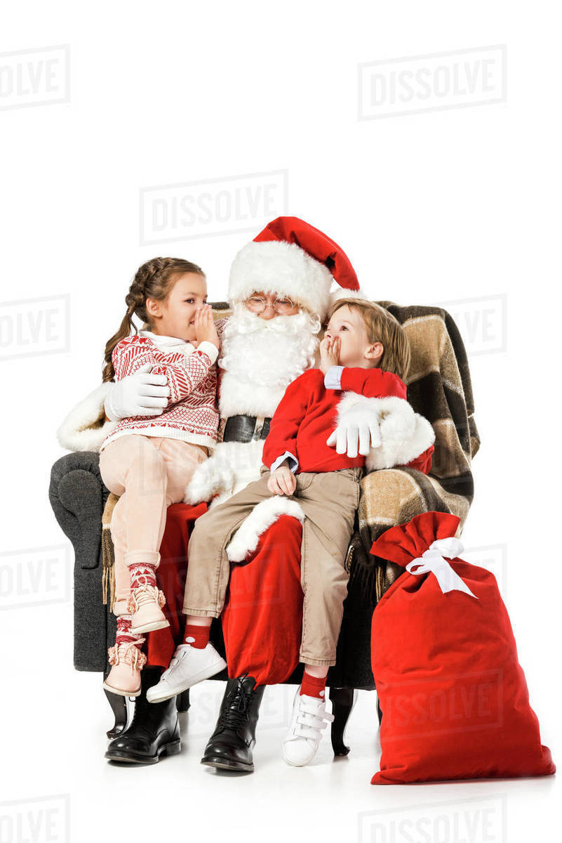 Kids whispering to santa while they sitting in armchair together ...