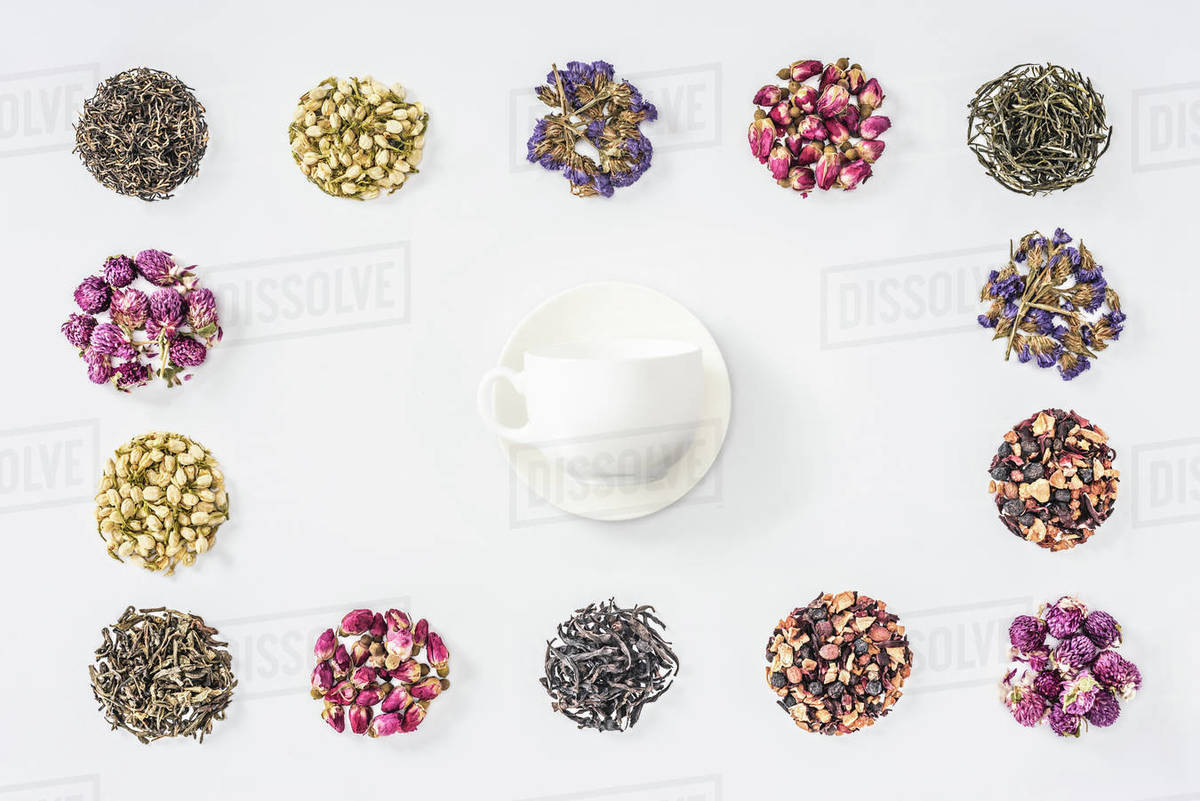 Elevated view of cup and plate in frame of dried herbal organic tea ...