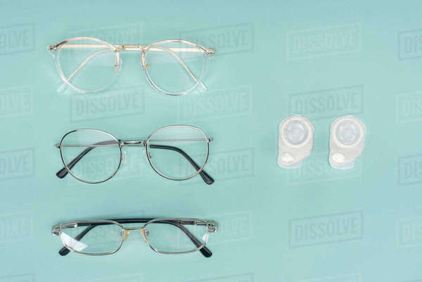 Top view of eyeglasses and contact lenses containers arranged on blue ...