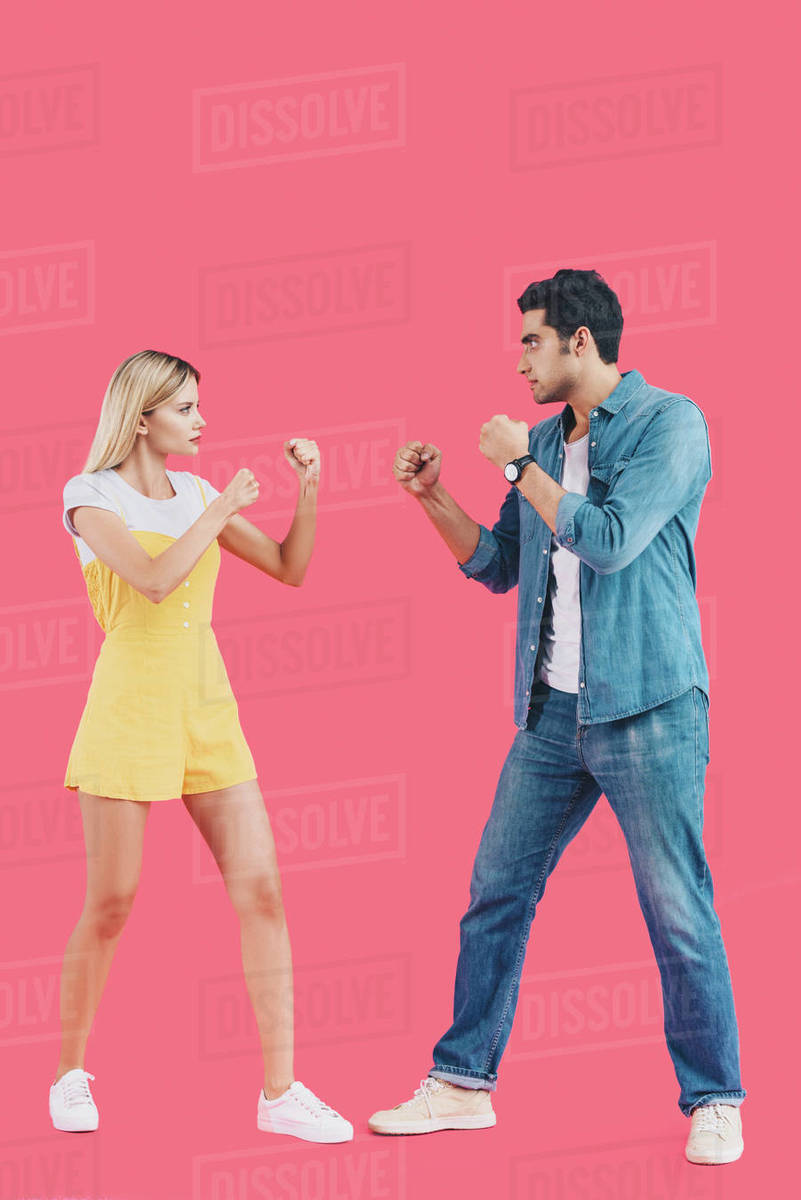 Side view of young couple standing in fight position and looking at ...