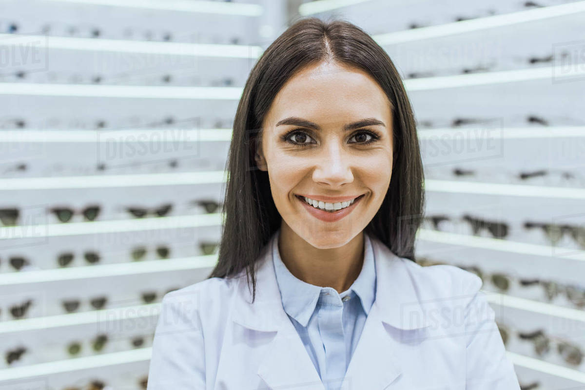 Professional smiling optometrist in white coat looking at camera ...