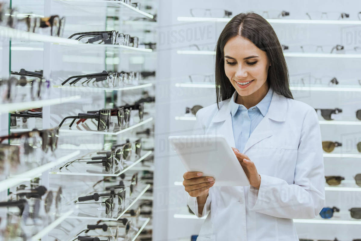 Professional optometrist using digital tablet near shelves with ...
