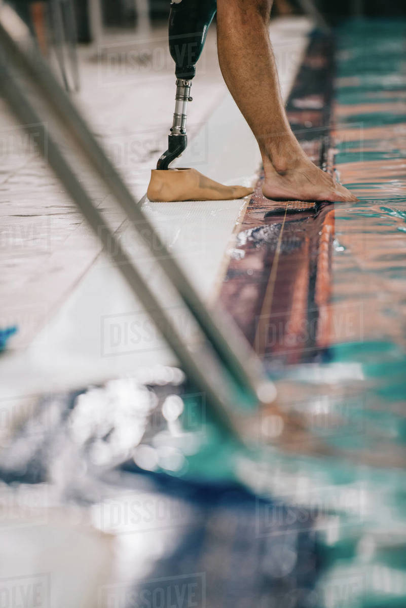 Cropped shot of swimmer with artificial leg standing on poolside at ...