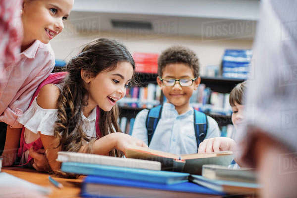 excited little children looking at book in library - Stock Photo - Dissolve