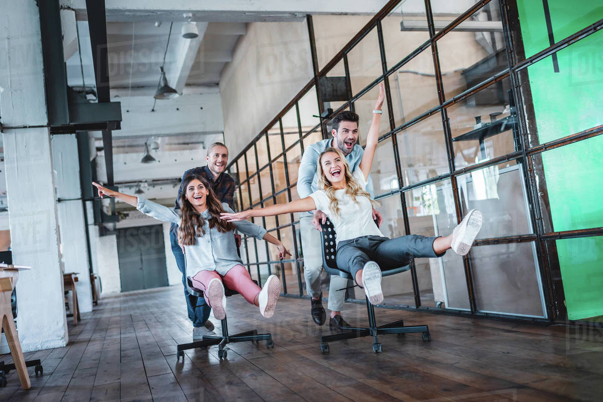 Cheerful young colleagues having fun together at workspace - Stock ...