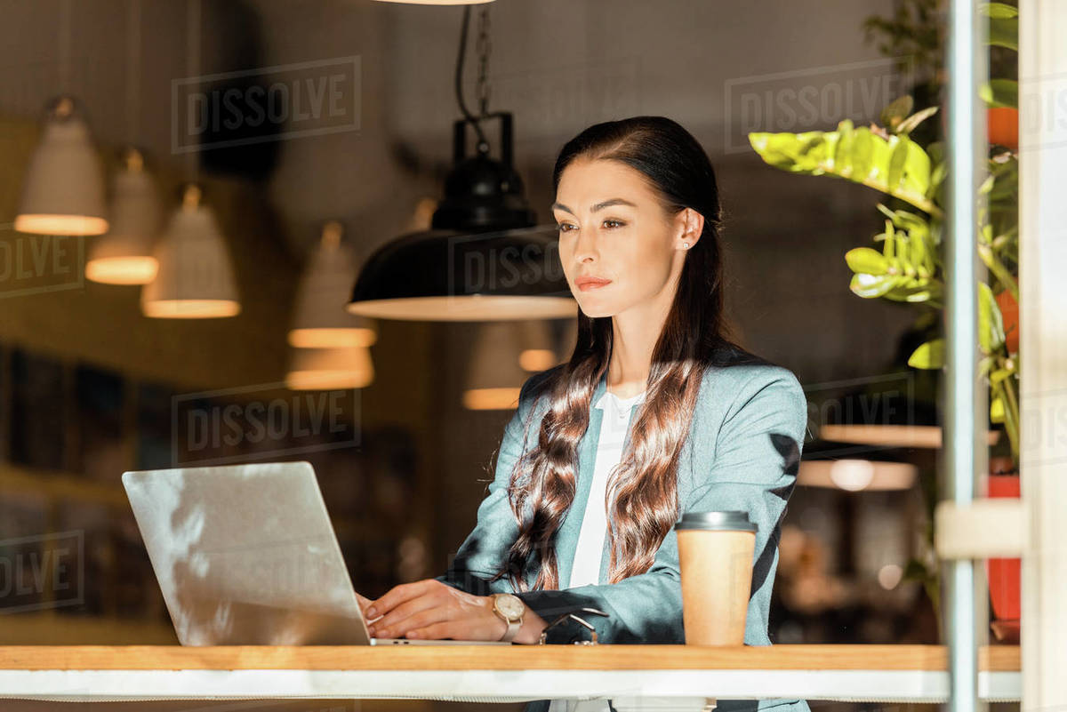 Attractive brunette freelancer working with laptop at coffee shop ...