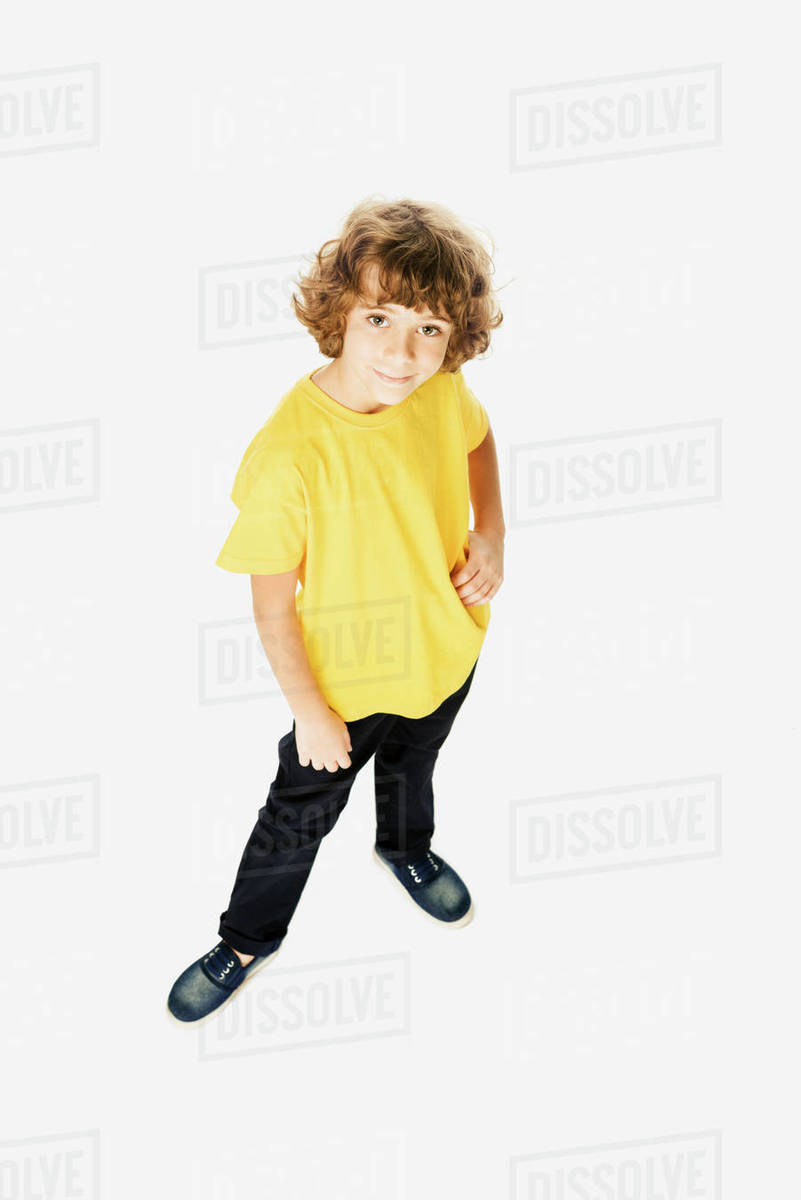 High angle view of cute little boy standing with hand on waist and ...