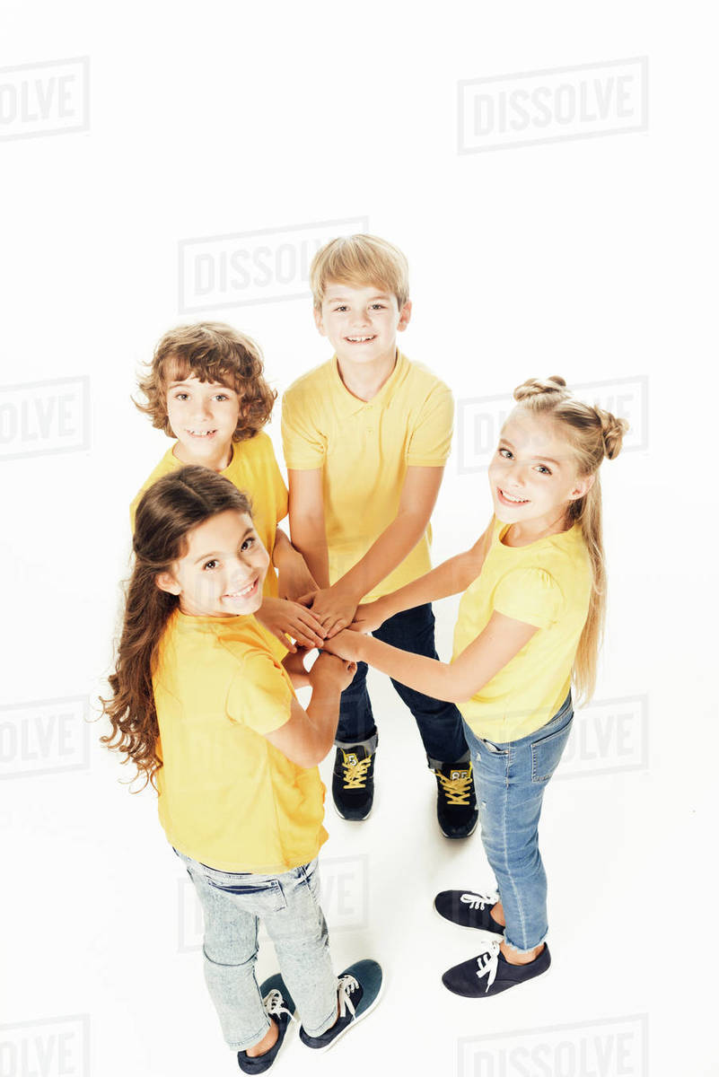 High angle view of adorable happy children stacking hands and smiling ...