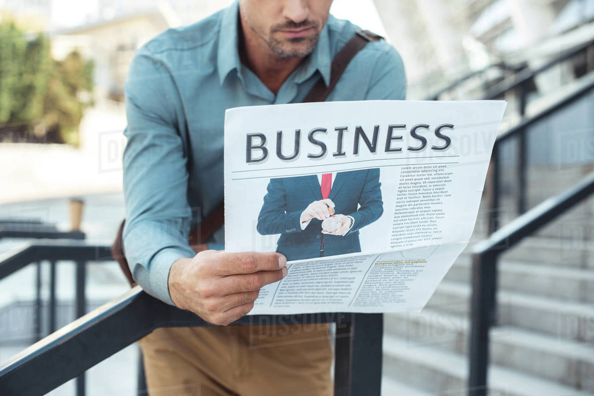 Cropped shot of middle aged man leaning at railing and reading business ...