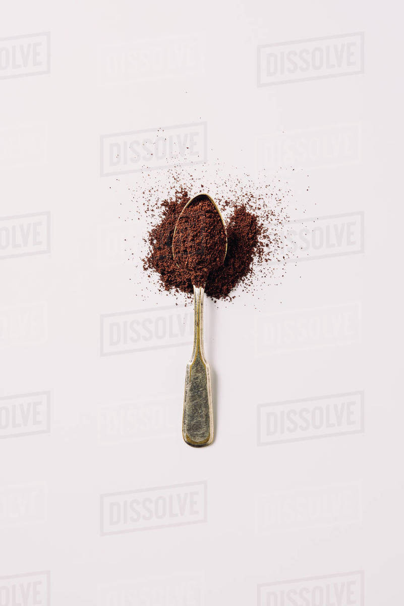 Top view of metal spoon with grinded coffee on white surface - Royalty ...