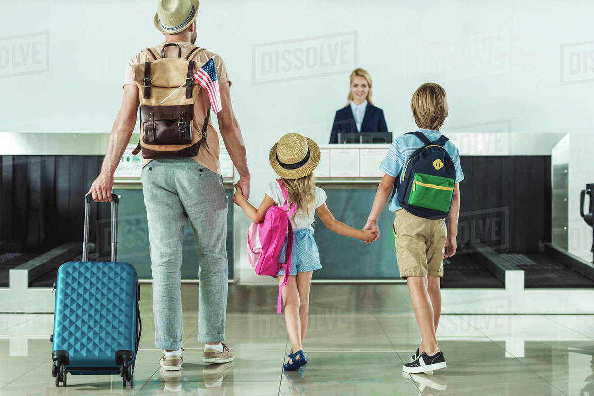 Back view of family with backpacks going to check in desk at airport ...