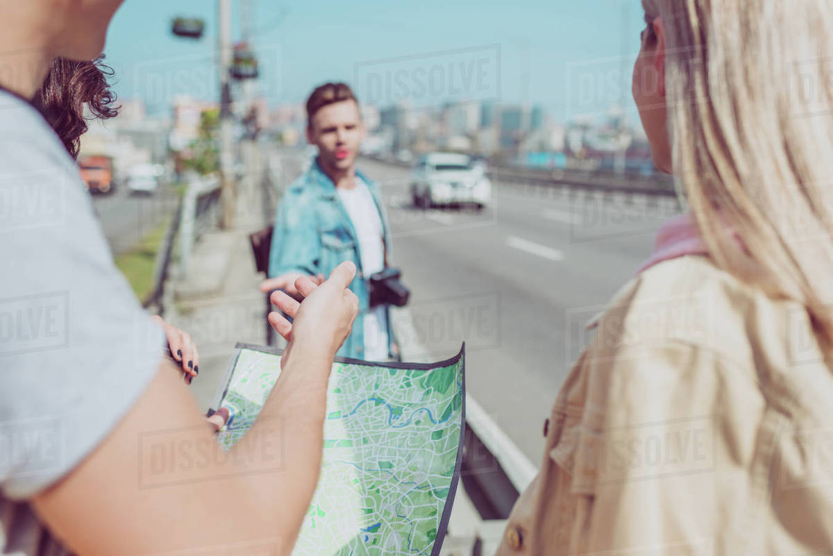 Partial view of travelers looking for destination on map during trip in ...