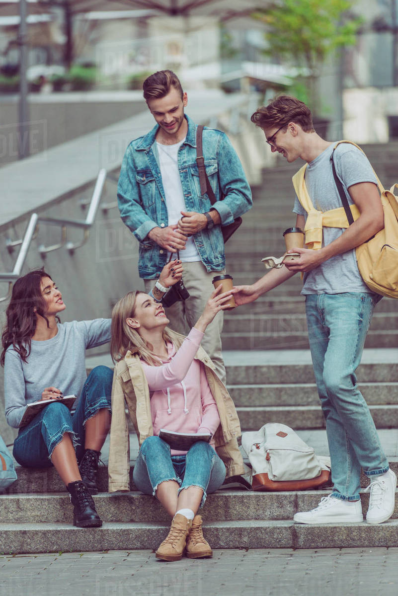Men brought coffee to go to friends on street steps in new city - Stock ...