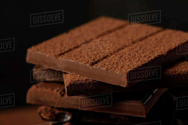 Close-up view of delicious assorted chocolate bars with cocoa powder on ...
