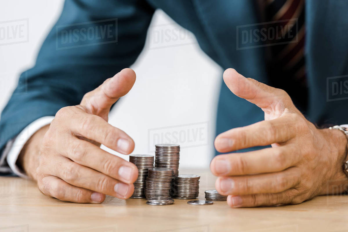 Businessman grabbing silver coins at wooden table - Royalty-free Stock ...