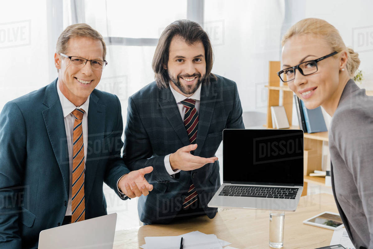 Young smiling male insurance agent standing with workers and pointing ...