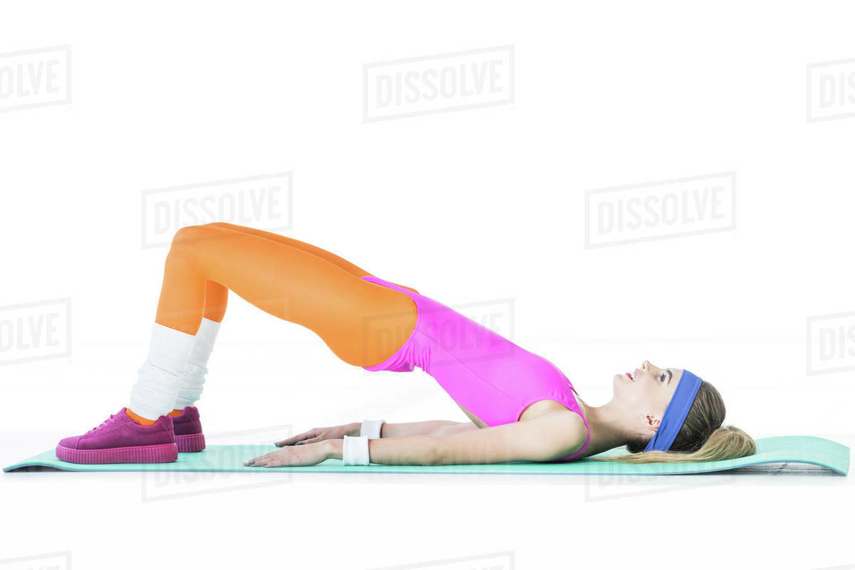 Side view of smiling sporty girl lying and training on yoga mat ...