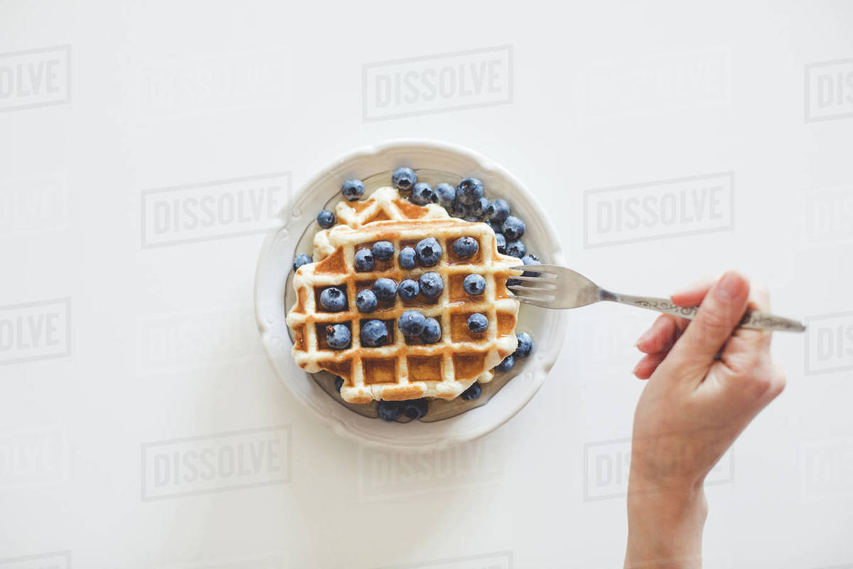 Top view of woman eating waffles with blueberries for breakfast ...