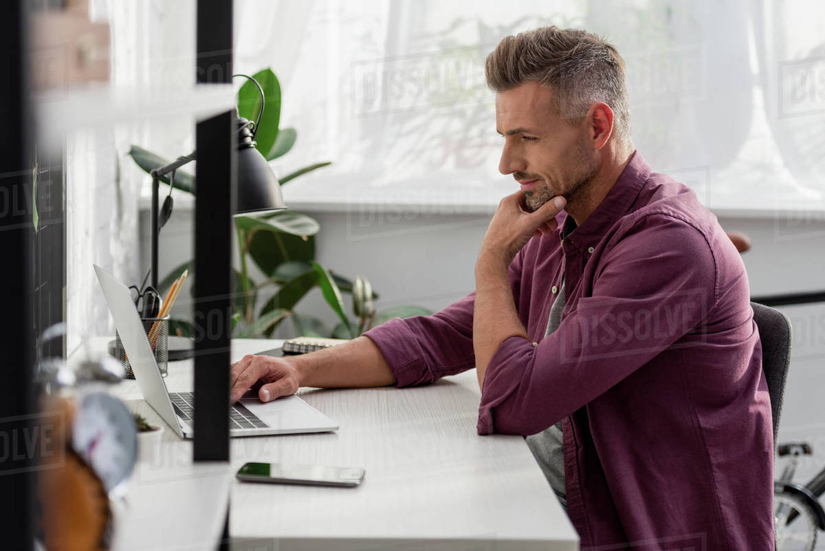 Man sitting on chair and working on laptop at workplace - Royalty-free ...