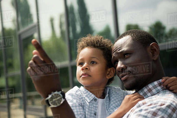 african american father and son looking away and pointing with finger ...