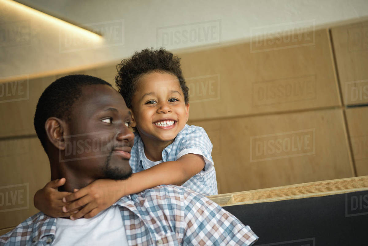 adorable african american boy hugging father and smiling at camera ...