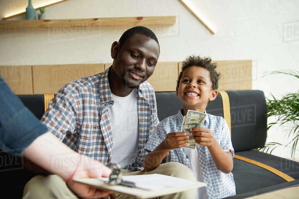 cropped shot of waiter giving bill to smiling father and son with ...