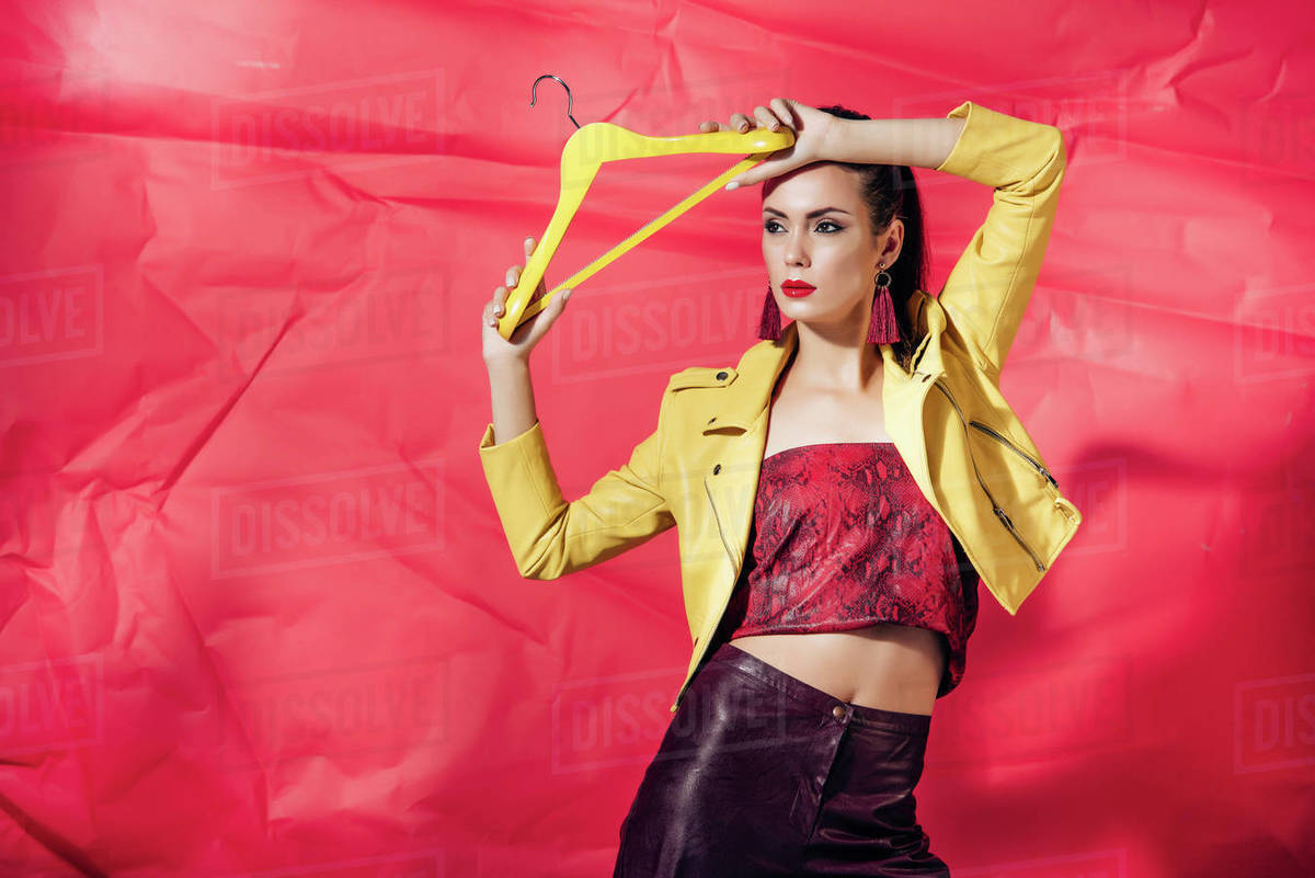 Beautiful stylish model in yellow leather jacket posing with hanger on ...