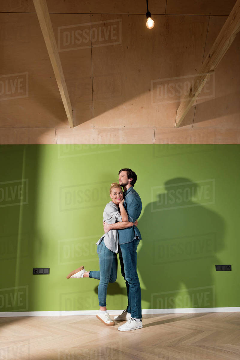 Loving family couple hugging by green wall in apartment - Royalty-free ...