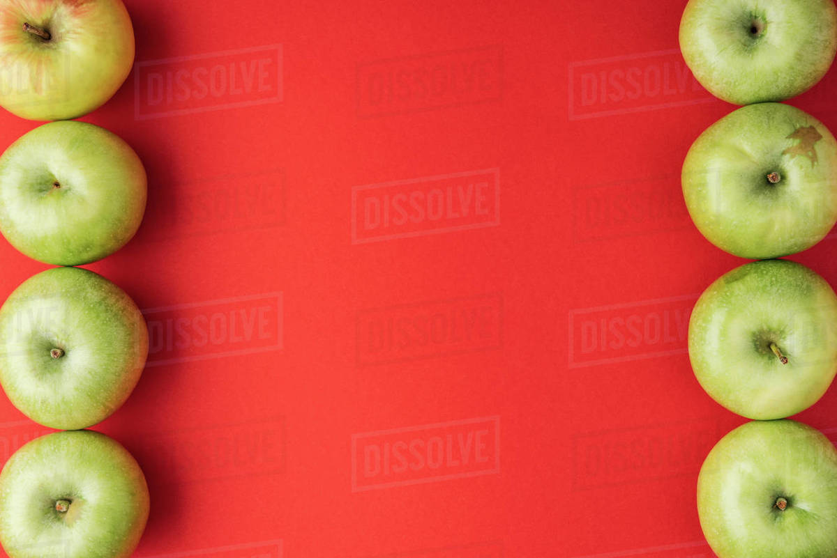 vertical frame of ripe green apples on red background - Stock Photo ...