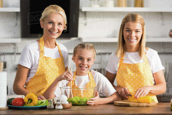 adorable happy child with mother and granmother smiling at camera while ...