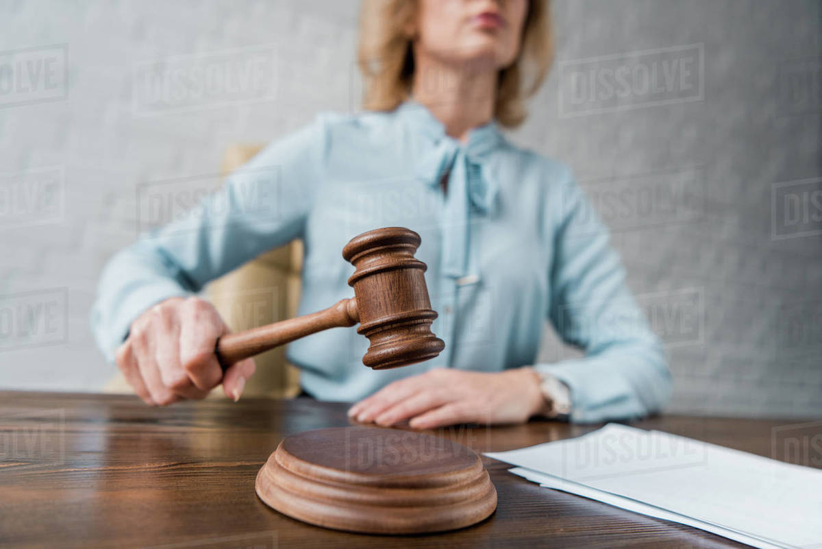 Cropped shot of female judge holding wooden hammer at workplace ...