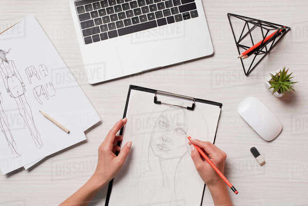 office desk with laptop, art supplies and cropped view of designer ...