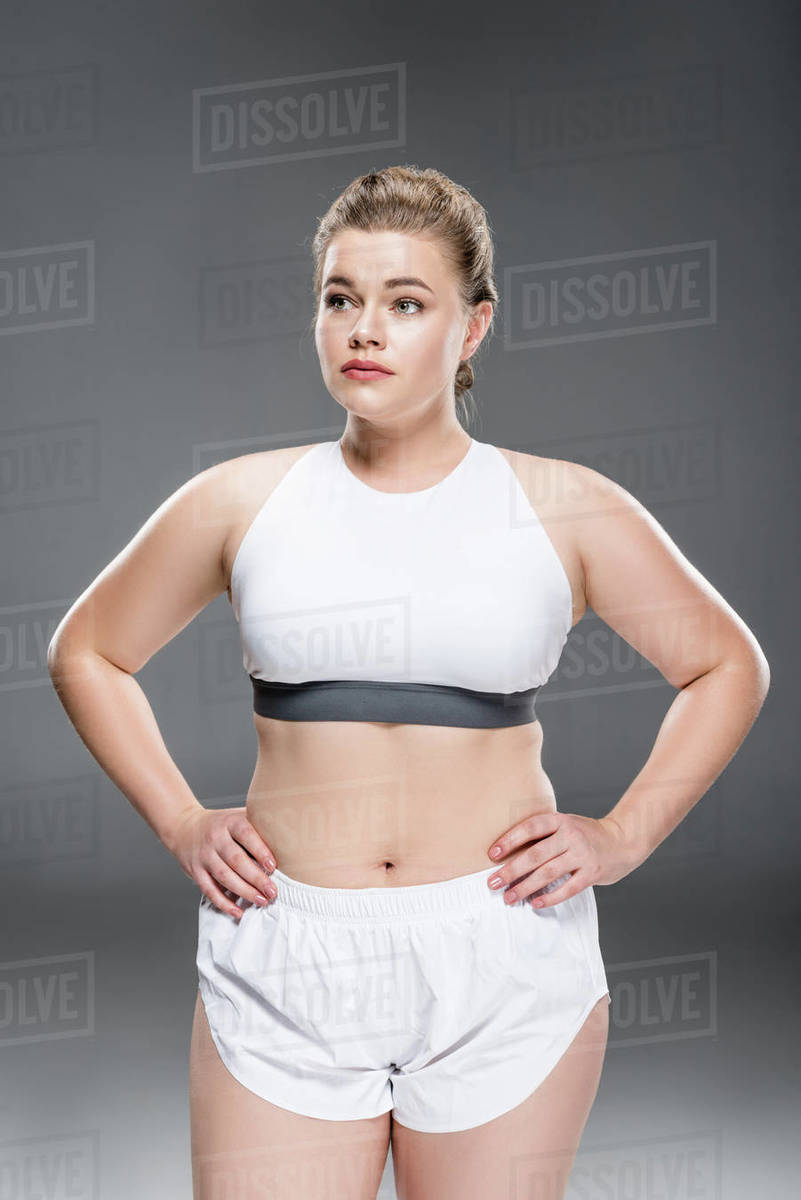 Attractive young oversize woman in sportswear standing with hands on ...