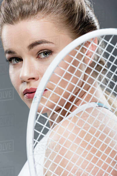 Close-up view of young woman holding tennis racket and looking at ...