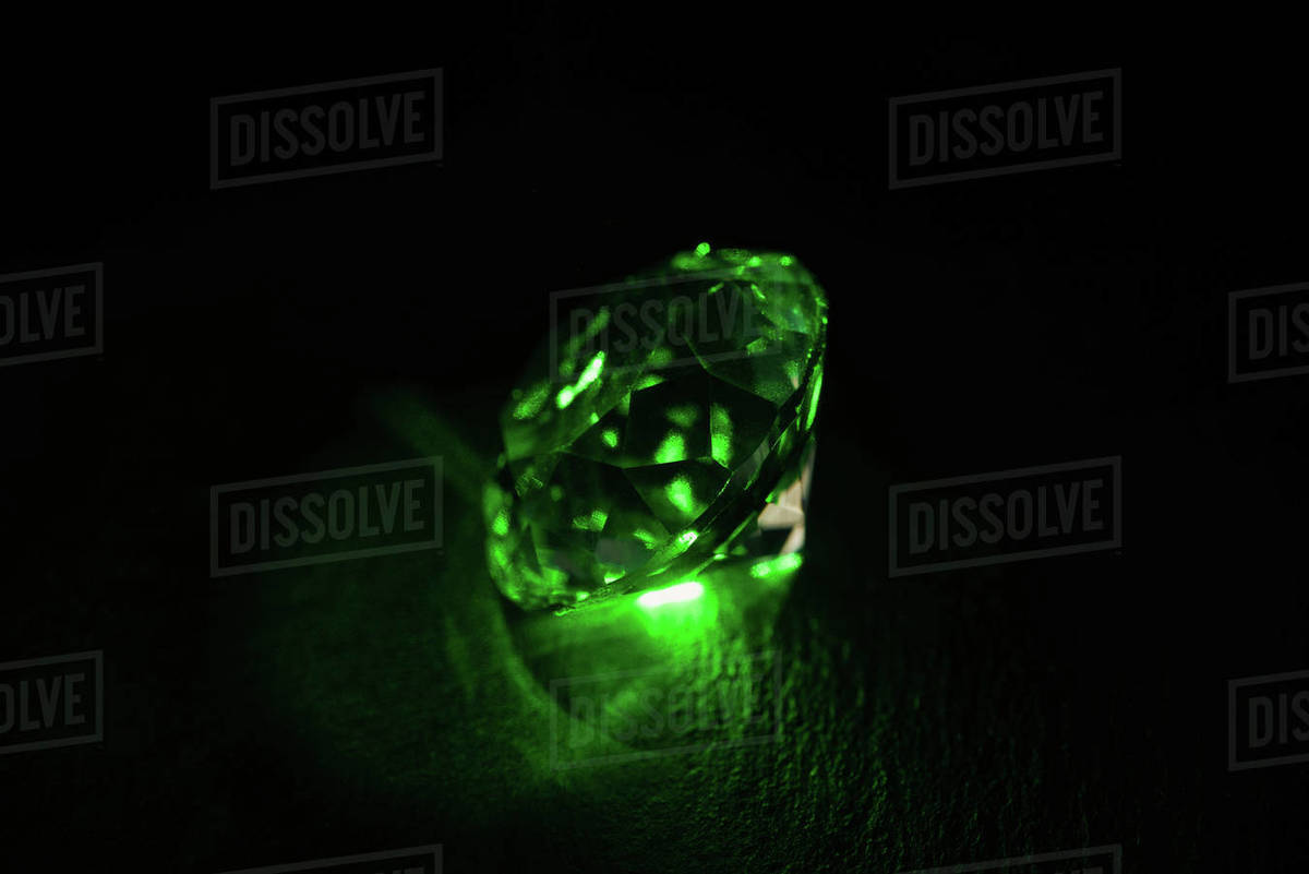 Illuminated diamond with bright green neon light on dark background ...
