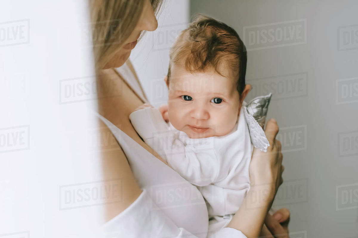 Selective focus of cheerful mother carrying little baby boy at home ...