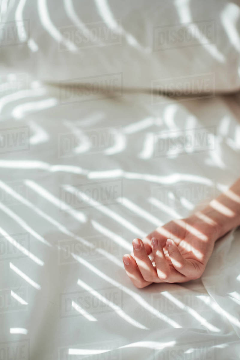 Cropped shot of female hand on white bed sheet - Stock Photo - Dissolve