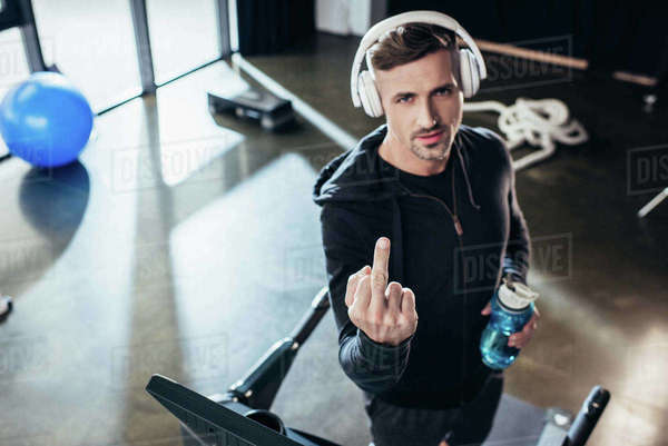 High angle view of handsome sportsman in hoodie showing middle finger ...