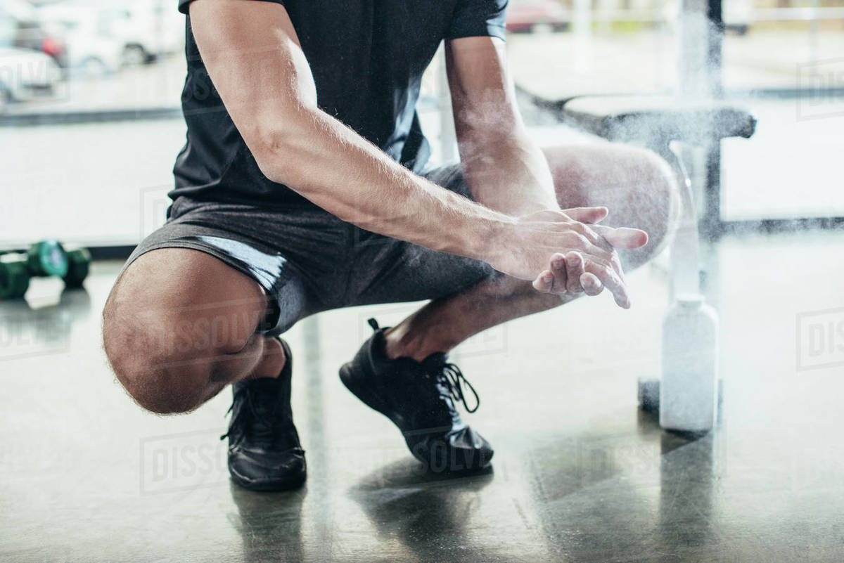 Cropped image of sportsman applying talcum powder on hands before ...